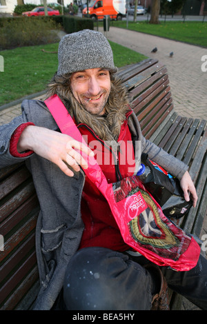 Crazy and happy homeless wanderer sitting on bench outside Stock Photo ...