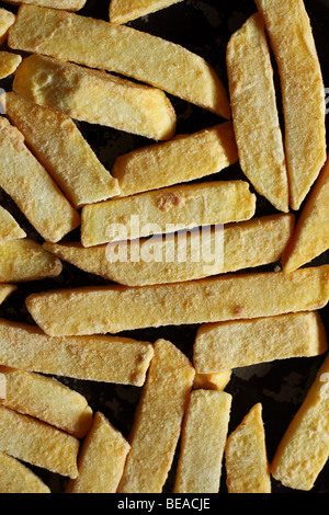Over chips pre cooked frozen chipped potatoes on a baking tray ready ...