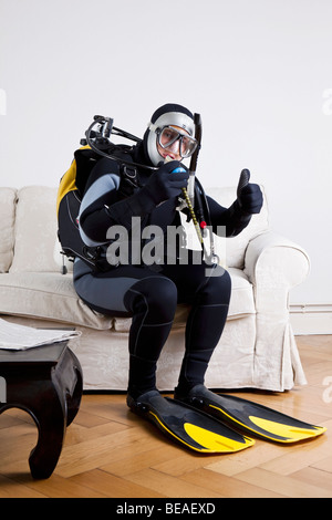 A scuba diver sitting on a couch reading a book Stock Photo - Alamy