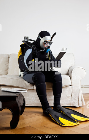 A scuba diver sitting on a couch in a living room giving a thumbs up ...
