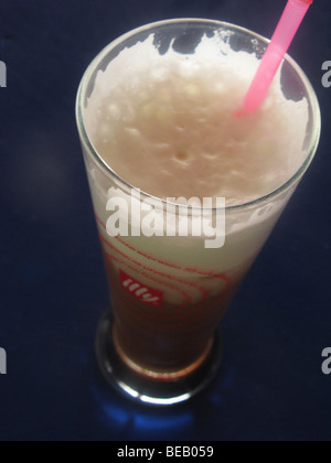 A vertical closeup of a refreshing iced coffee in a glass next to ...