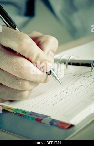 Notebook and pen in hand on pink background with copy space.Business ...