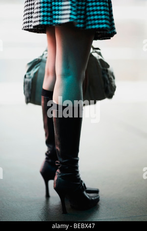 Side view of woman with bag standing on city street during sunny day ...