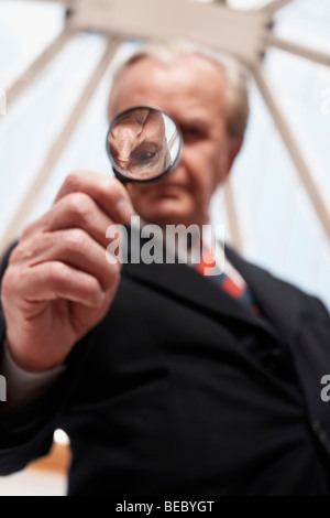 selective focus of man holding magnifying glass near coins on plaid ...