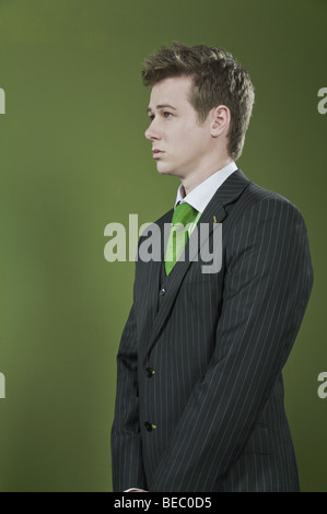 Side view of young businessman in suit standing against white ...