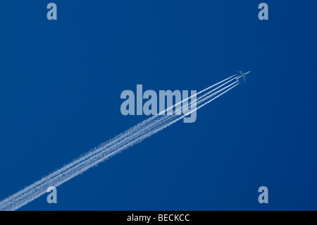 Four-engine airliner drawing a contrail in a clear blue sky Stock Photo ...