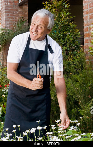 Man holding gardening pruning shears against alyssum flowers on orange ...