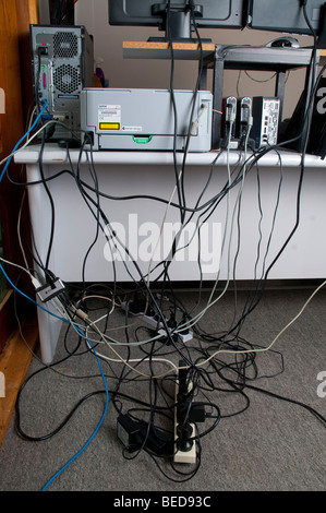 Tangle of computer wires, cables and plugs on an untidy office desk ...