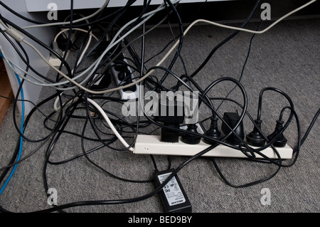 Tangle of computer wires, cables and plugs on an untidy office desk ...