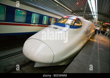 A sleek white high-speed train at a station platform under a modern ...
