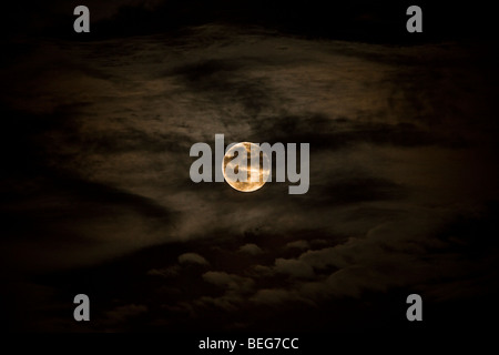 Full moon behind clouds warm yellow color Stock Photo - Alamy
