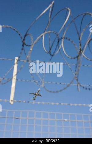 An airliner crosses the razor-wired perimeter fence at Heathrow Airport ...