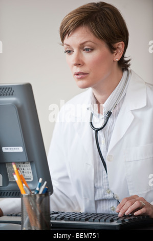 Professional female medical doctor working at her desk using laptop ...