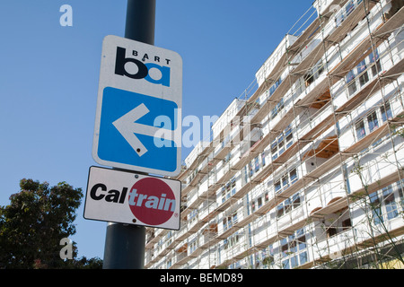 A low angle view of BART and Caltrain road signs by a scaffolded condo ...