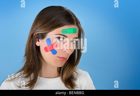Beautiful woman with colored bandages on the face over a blue ...