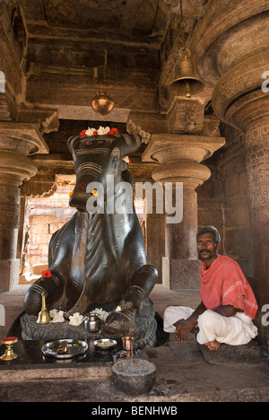 Man sitting next to a Monolith Nandi Statue in Nandi Mandapa Pattadakal ...