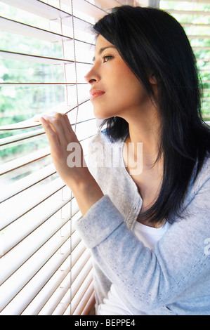 A young woman peering through Venetian blinds Stock Photo - Alamy