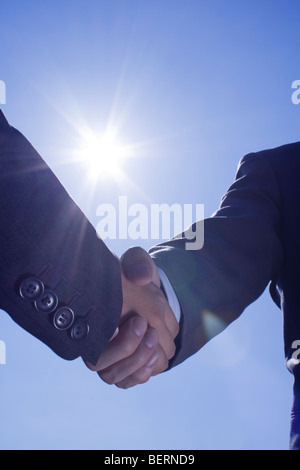 Two businessmen shaking hands under the sun Stock Photo - Alamy