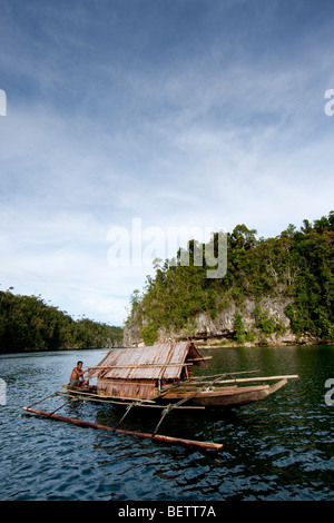 Native in outrigger canoe Stock Photo - Alamy