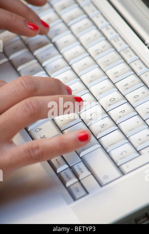 Woman typing with fingers on keyboard at a desktop computer amid ...