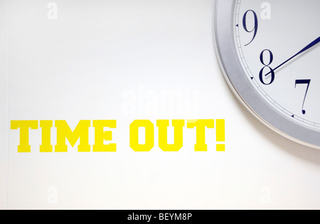 Wall clock with slogan relating to time on a white wall Stock Photo - Alamy