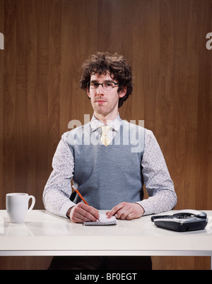 Image of pensive young man writing down ideas in planner, looking ...