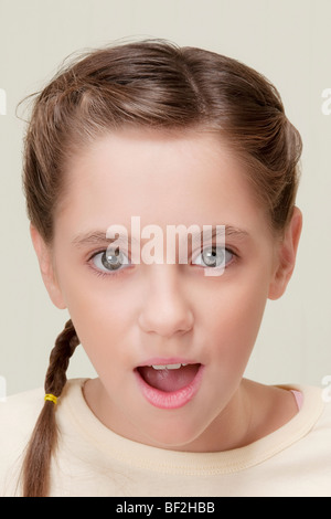 Portrait of tween girl with surprised face holding hand on cheek blurry ...