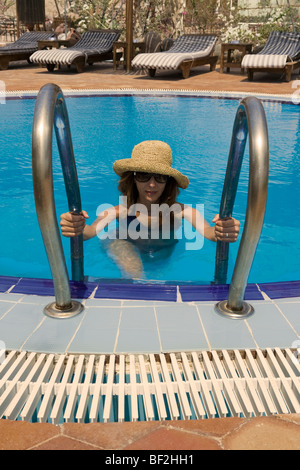 Young woman is exiting a swimming pool, eyes closed and face to the sun ...