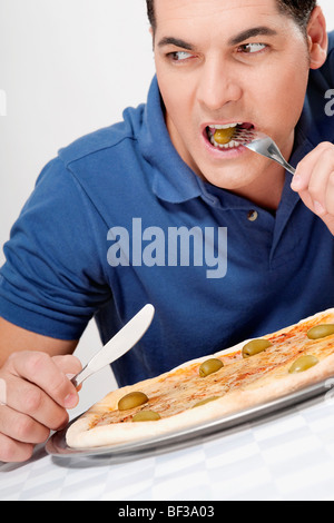 Man eating pizza with a fork and knife Stock Photo - Alamy