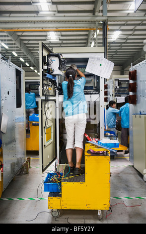 A factory worker installing a part of an electrical panel in an ...