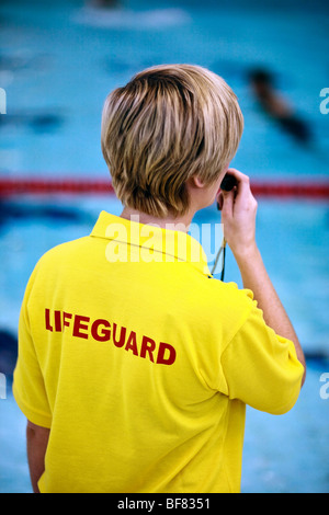 Female lifeguard watching swimmers at an indoor swimming pool in the UK ...