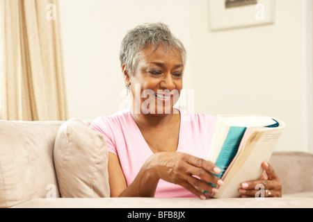 Senior woman reading a book in the comfort of her home. Close up no ...