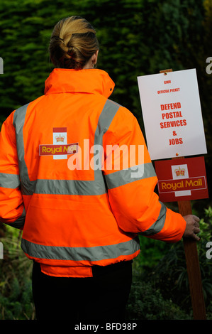 A female Royal Mail postal worker delivering post to a house on her ...