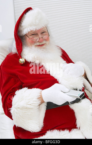 Santa Claus holding tv remote control Stock Photo - Alamy