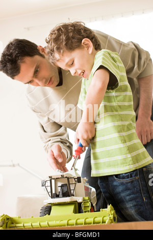 father fixing toy with son Stock Photo - Alamy
