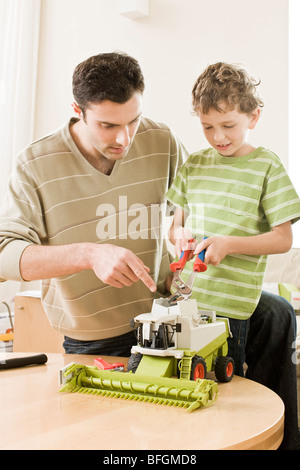 father fixing toy with son Stock Photo - Alamy