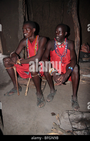 Two masai men in traditional clothes standing under big mkungu tree ...