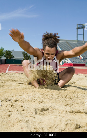 Young athlete landing in the sand pit during the long jump Stock Photo ...