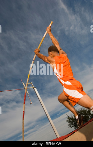Athlete holding a pole vault pole on a track field, focused and ...