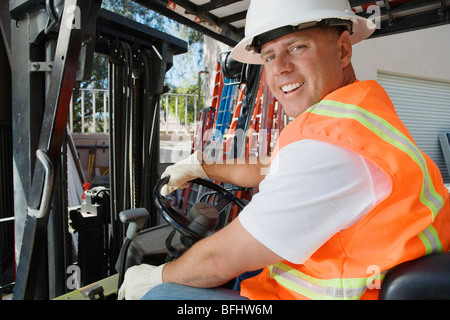 Portrait of a forklift driver wearing protective ear muffs while moving ...