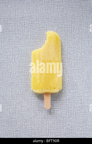 Single yellow summer popsicle with bite removed, isolated on a white ...