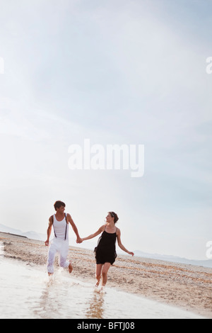 A man running along the shore splashing water on a beautiful sunny day ...