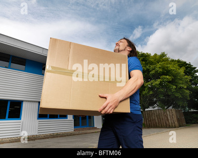 Man carrying heavy box Stock Photo - Alamy
