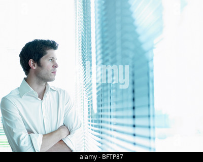 Worried man looking through window blinds into darkness. Paranoia ...
