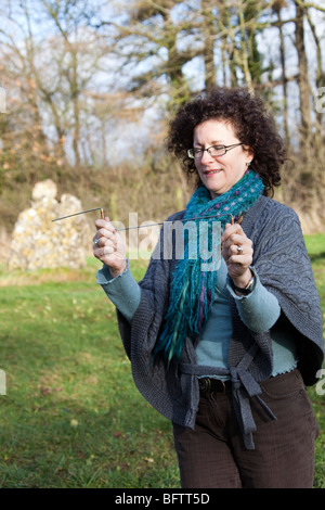 Woman Dowser with L-shaped metal dowsing rods practising at Rollright ...