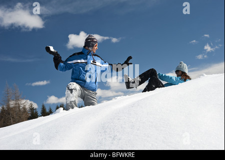 Young man, woman playing, throwing snowballs in winter snowstorm, storm ...