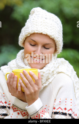 Portrait of young woman in balaclava with gun against red background ...