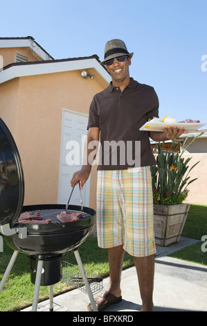 cooking barbeque, african american man turning the sausages with a fork ...
