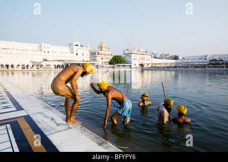 Sikh men taking a religious bath in Golden Temple, Amritsar, India ...