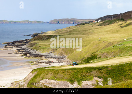A tractor cutting hay on a clifftop field at Coldbackie, Highland ...